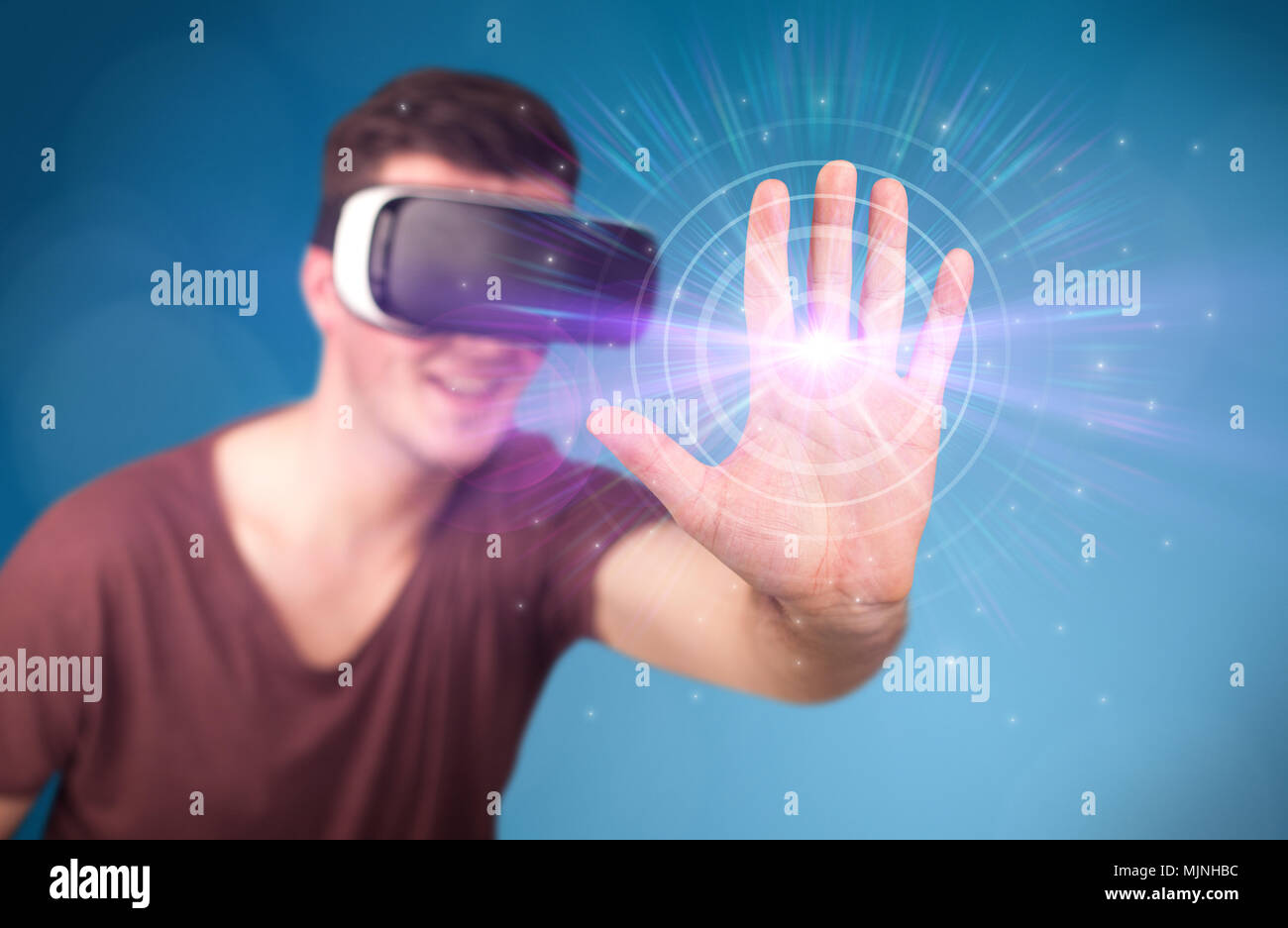 Young impressed man wearing virtual reality goggles with blue circles ...