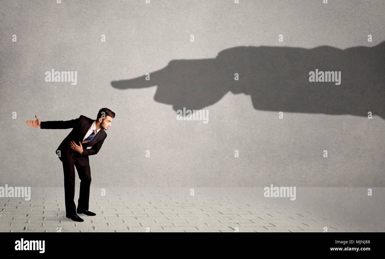 Business person looking at huge shadow hand pointing at him concept on ...