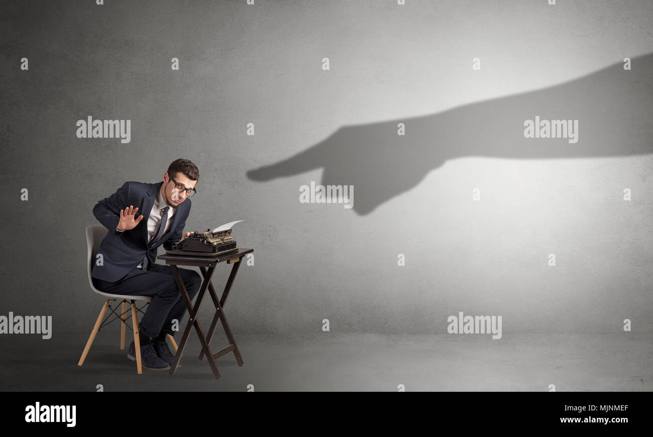 Shadow hand pointing at a small afraid worker Stock Photo - Alamy