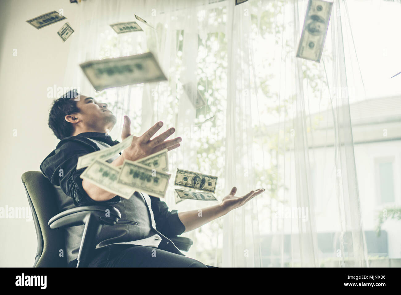 happy business man earned dollar bills us money under a money rain ...