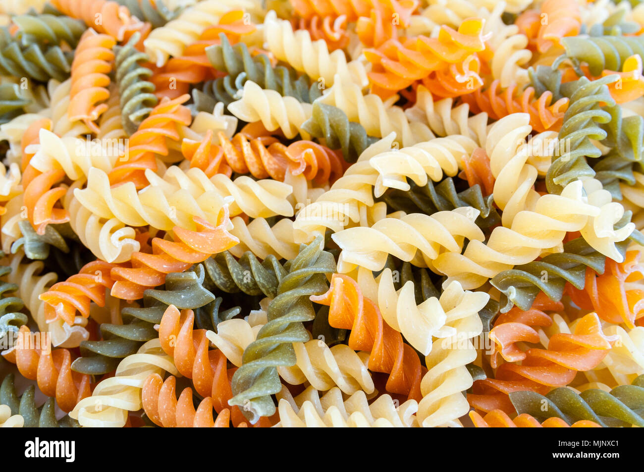 Dried tricolore fusilli pasta close up background Stock Photo - Alamy