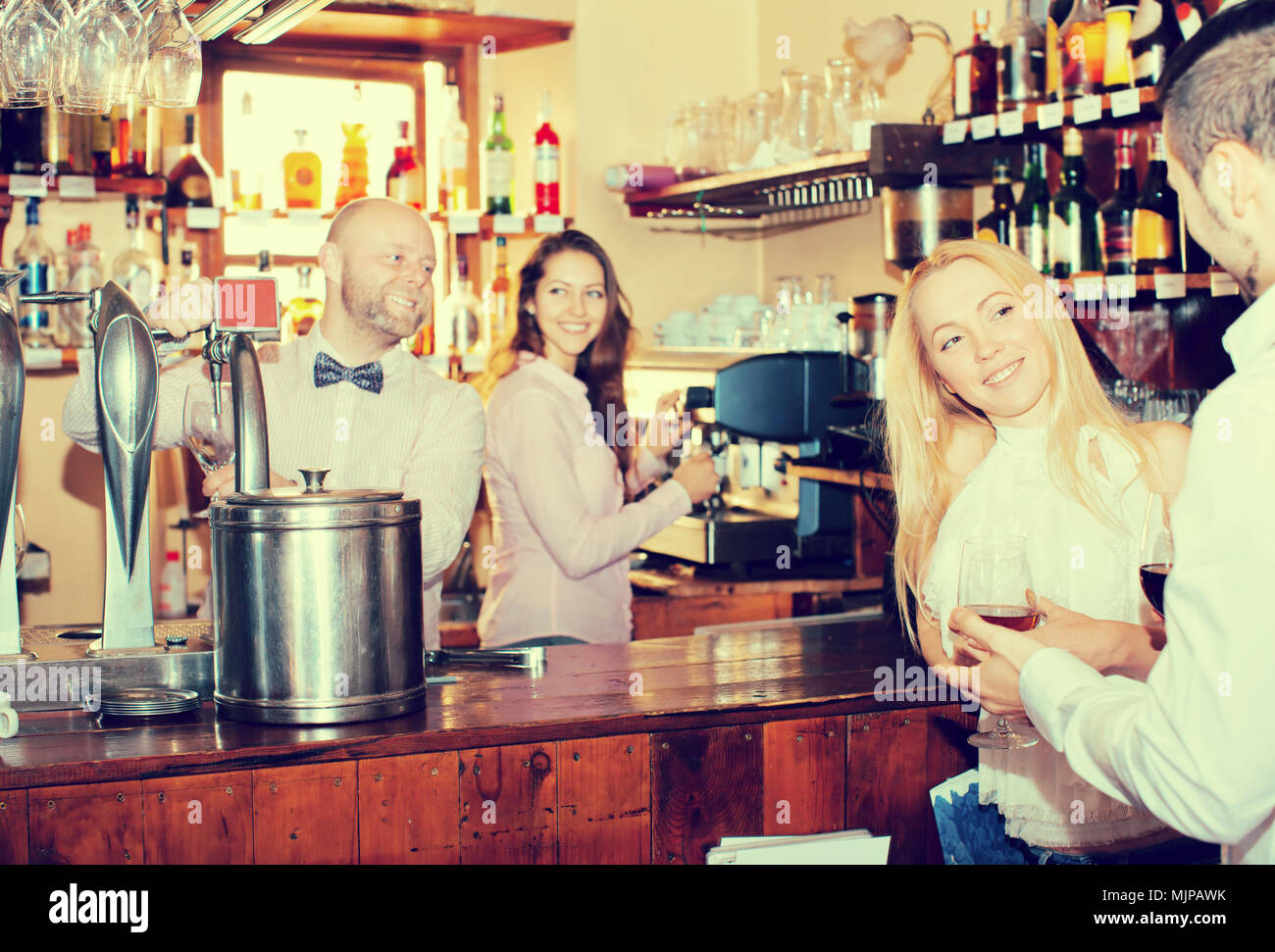 Happy bartender entertaining guests at the bar counter Stock Photo - Alamy