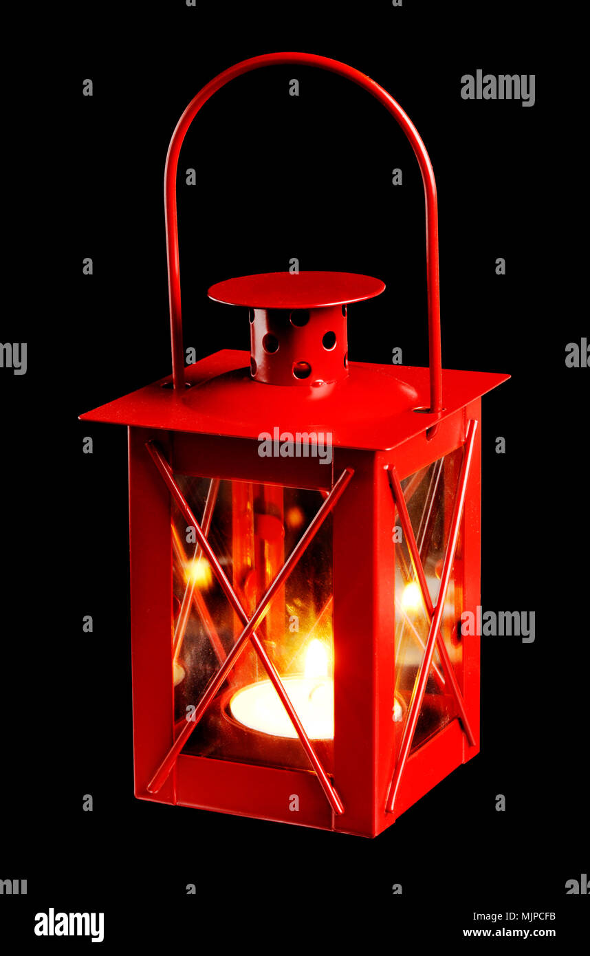 A small red lantern with a lighted candle isolated on black background ...