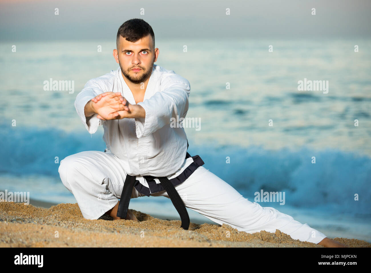 Male is practicing karate moves on the beach near the sea Stock Photo ...