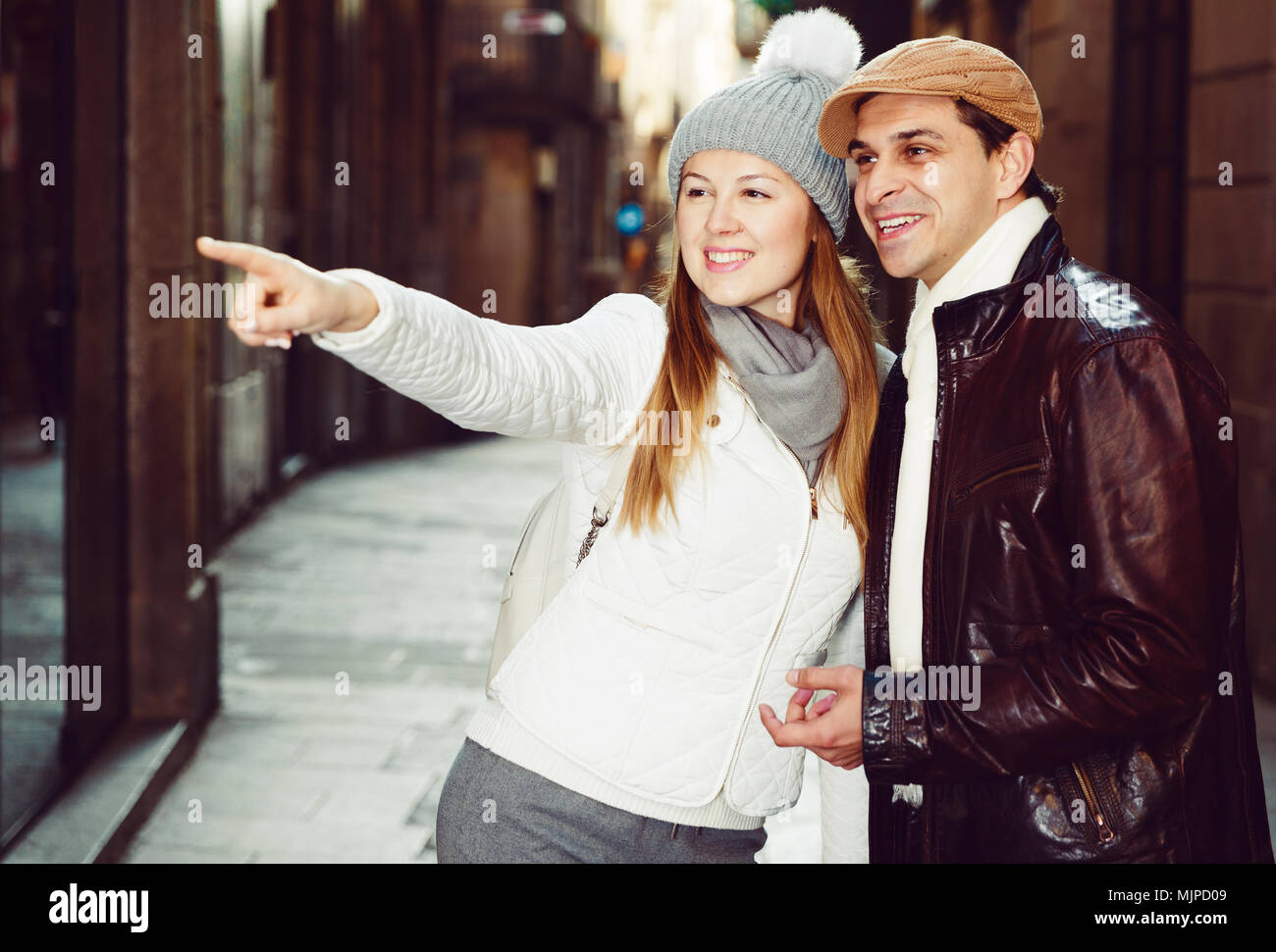 Adult tourists in hats and scarfs pointing finger on historical object ...