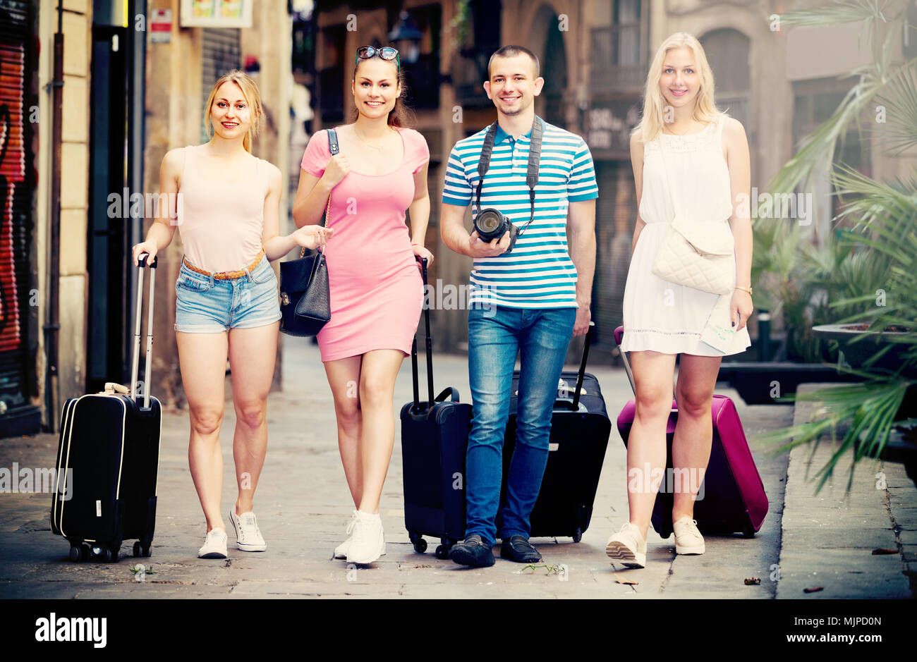 portrait of four happy people tourists taking walk in town together on ...