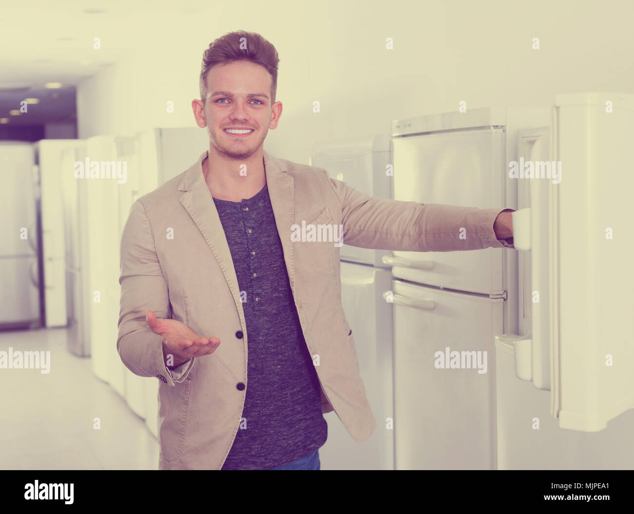 Happy young man selecting domestic refrigerator in supermarket Stock ...