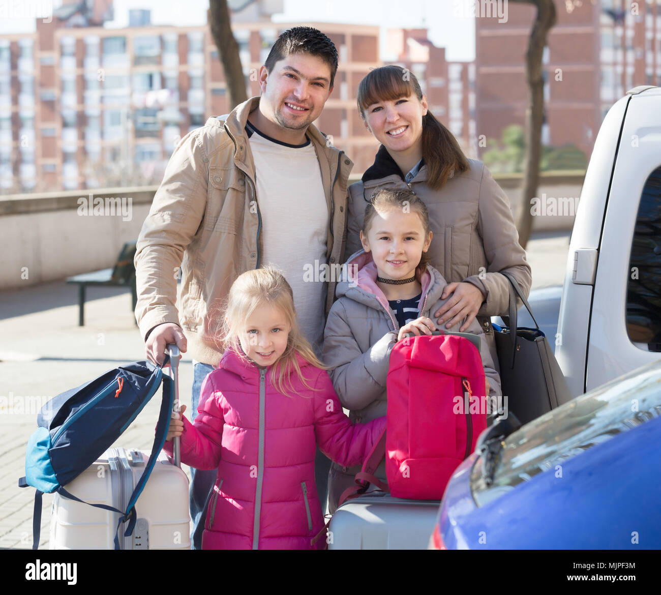 Smiling family with baggage at parking lot in spring day Stock Photo ...