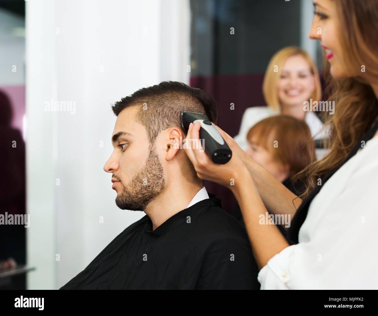 Haircutter makes the cut for young man in the hairdressing salon Stock ...