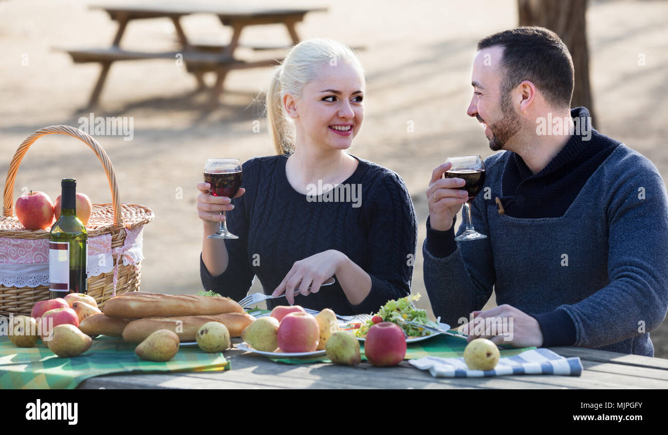 Portrait of young partners drinking wine at table in nature Stock Photo ...