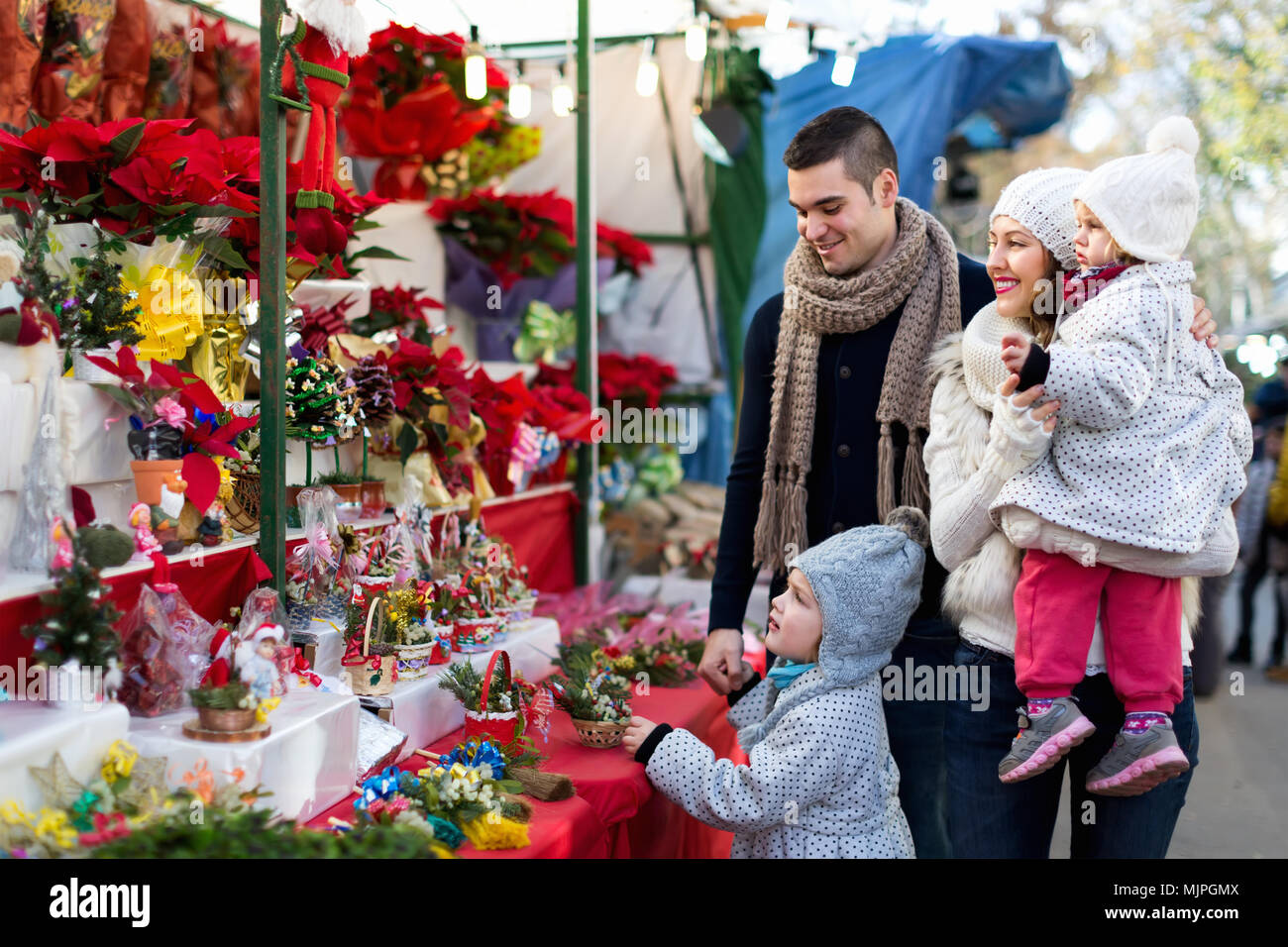Young married couple with two children choosing Christmas star flower ...