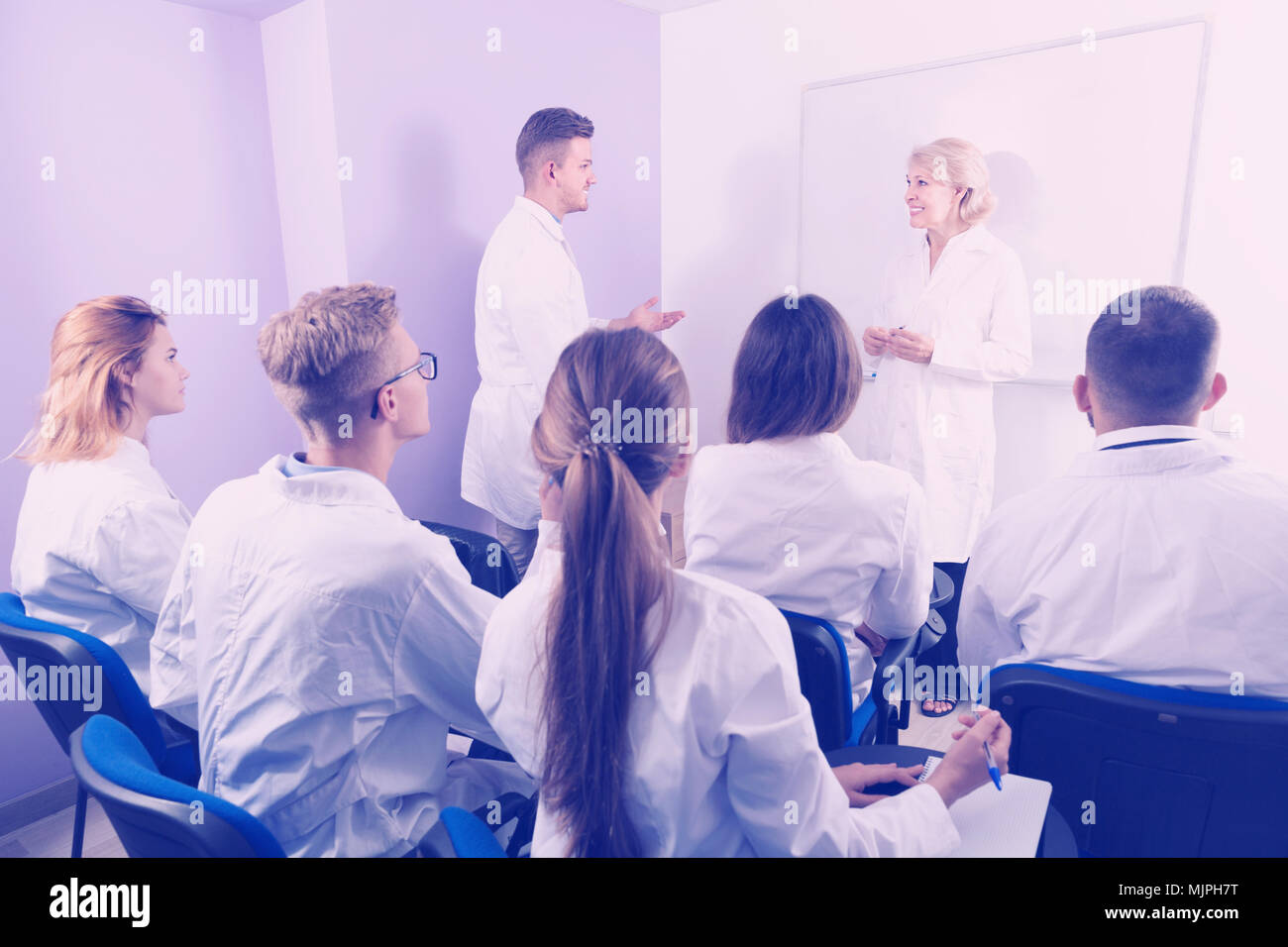 Confident male medical student talking with teacher in front of group ...
