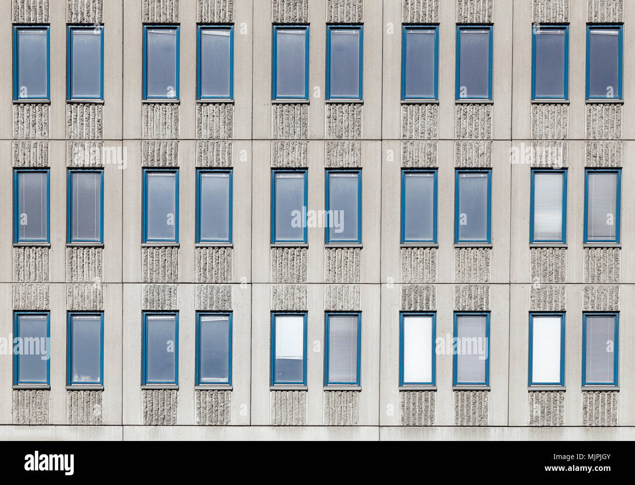 Elongated narrow windows in three rows of grooved concrete facade Stock ...