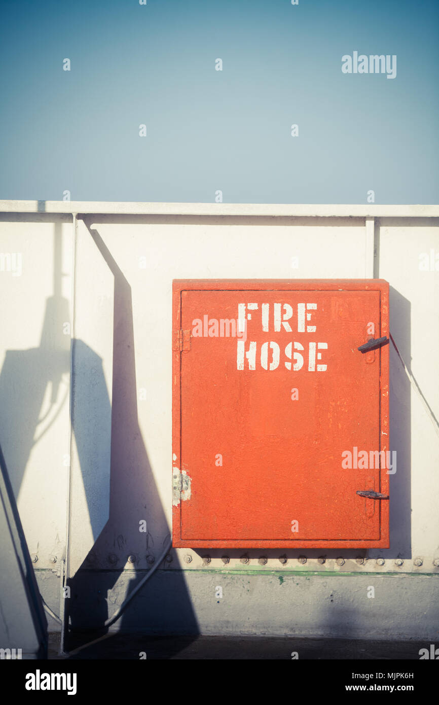 Color image of a red fire hose on a ship Stock Photo - Alamy