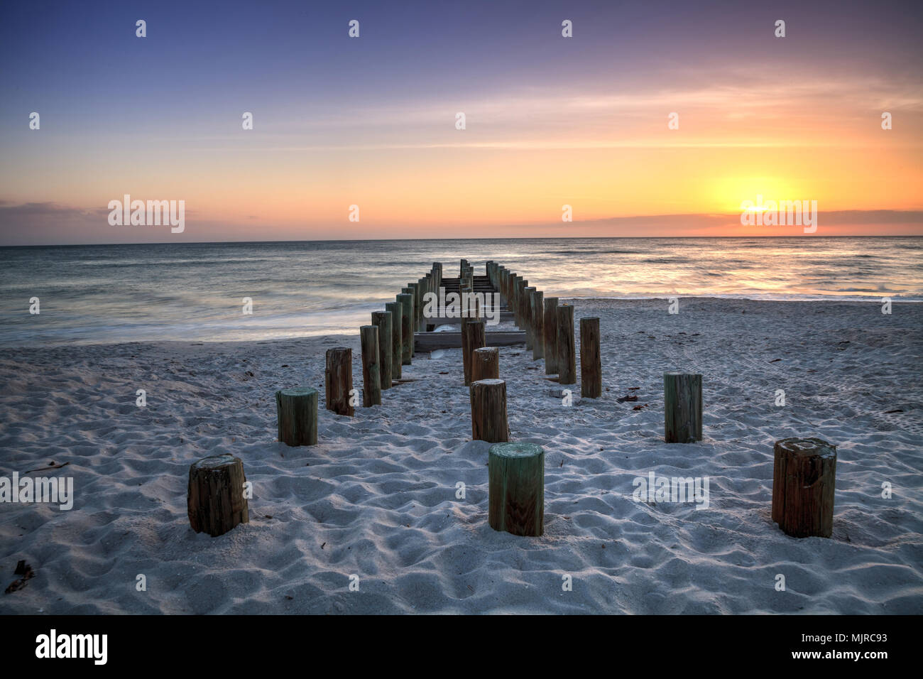Ruins of the old Naples Pier at sunset on the ocean on the beach of ...
