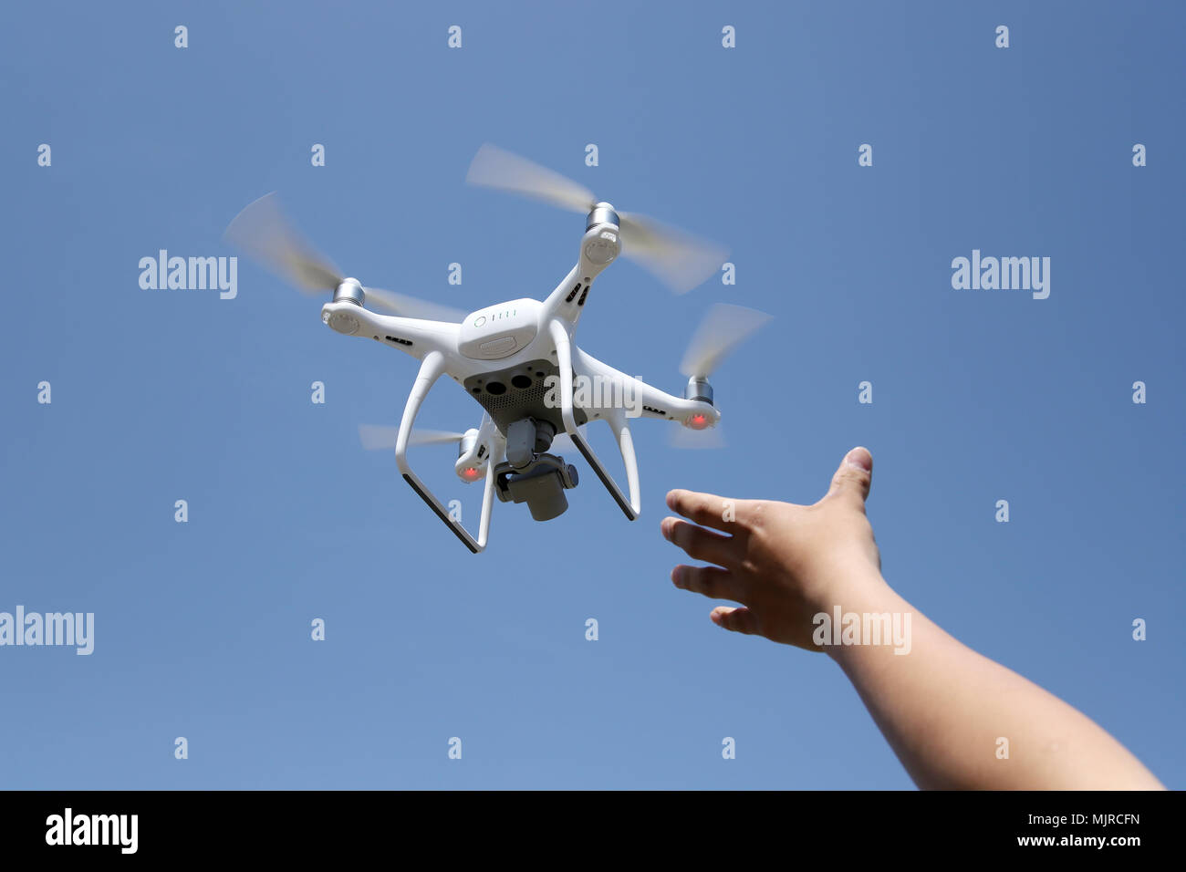 Hand catching drone aircraft in blue sky background, camera operator ...