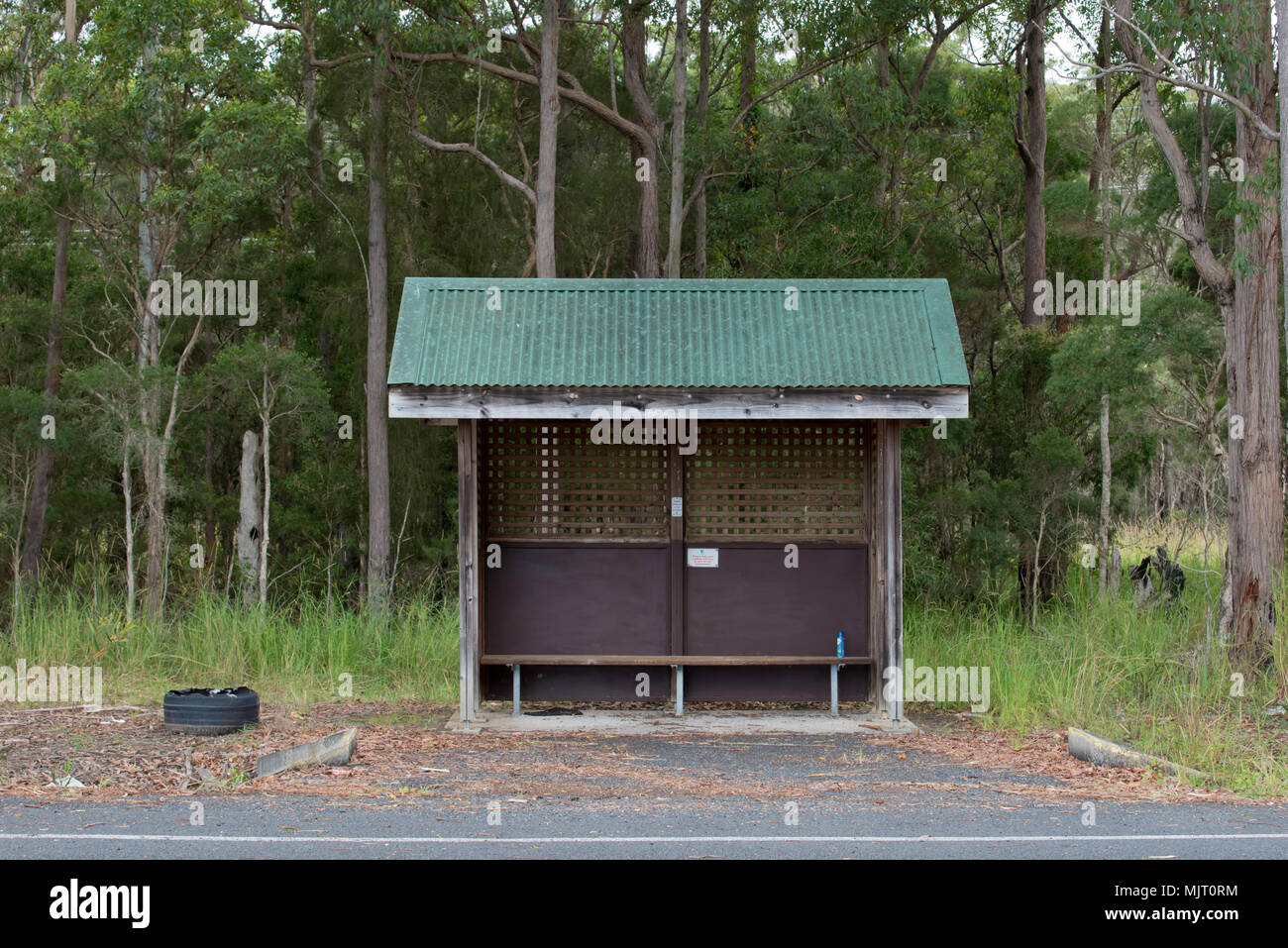 A lonely country bus stop in an Australian bush setting with litter and ...