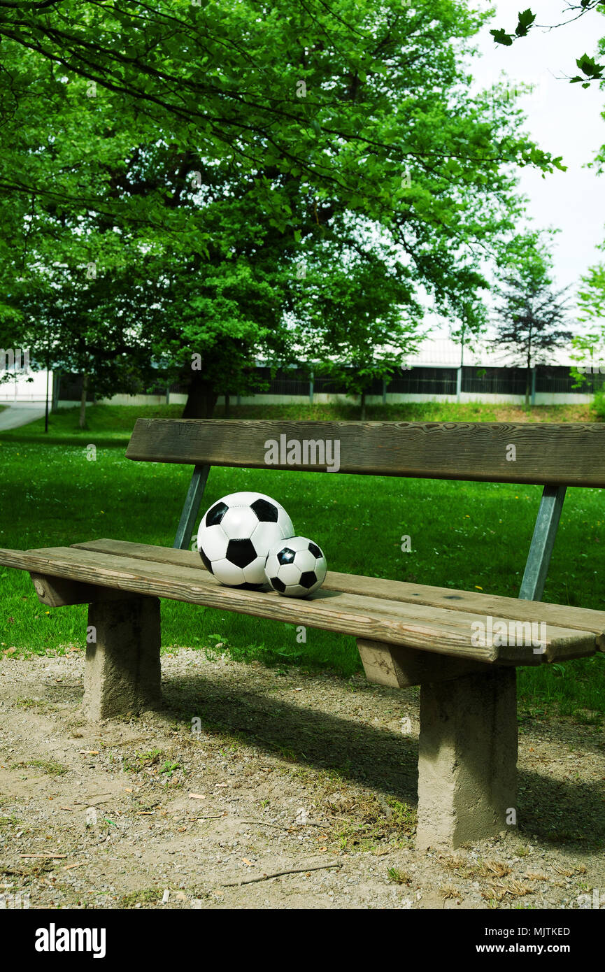 Two soccer balls on a park bench in the spring Stock Photo - Alamy