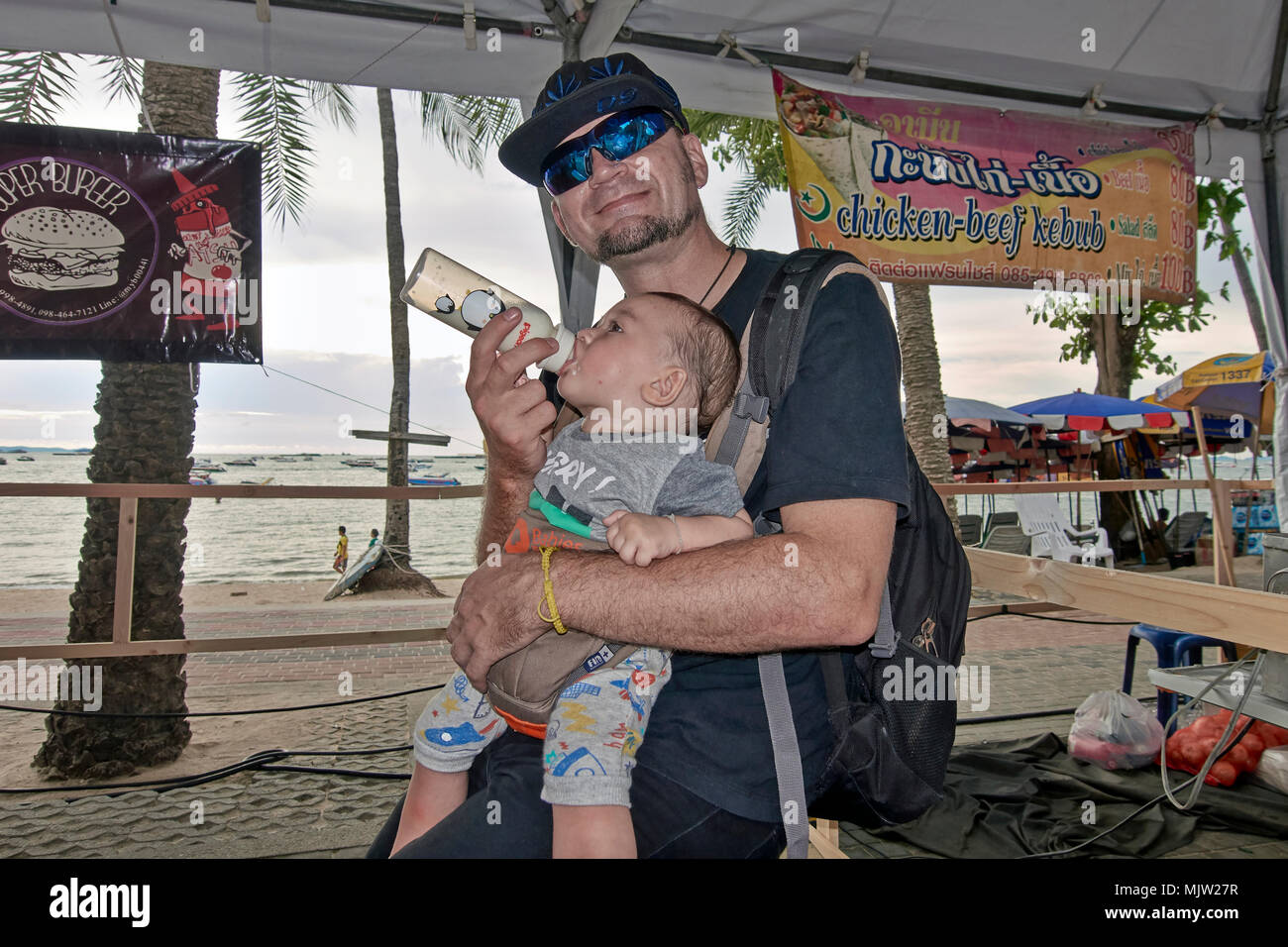 Father feeding baby milk from a bottle. Man feeding baby a drink ...