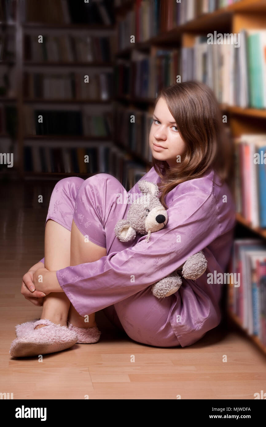 The girl in pink pajamas in the library among the books Stock Photo - Alamy
