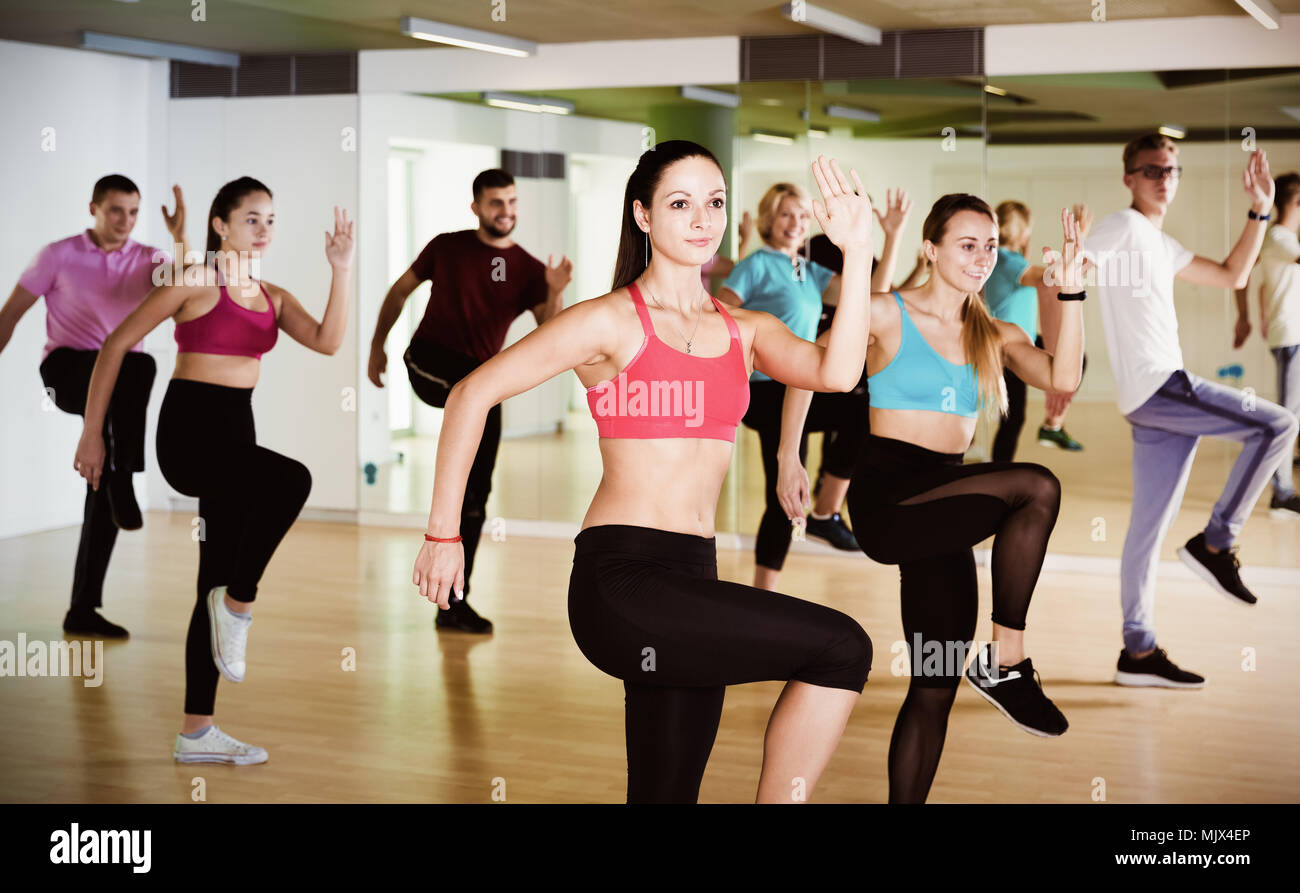 Cheerful people of different ages studying zumba dance elements in ...