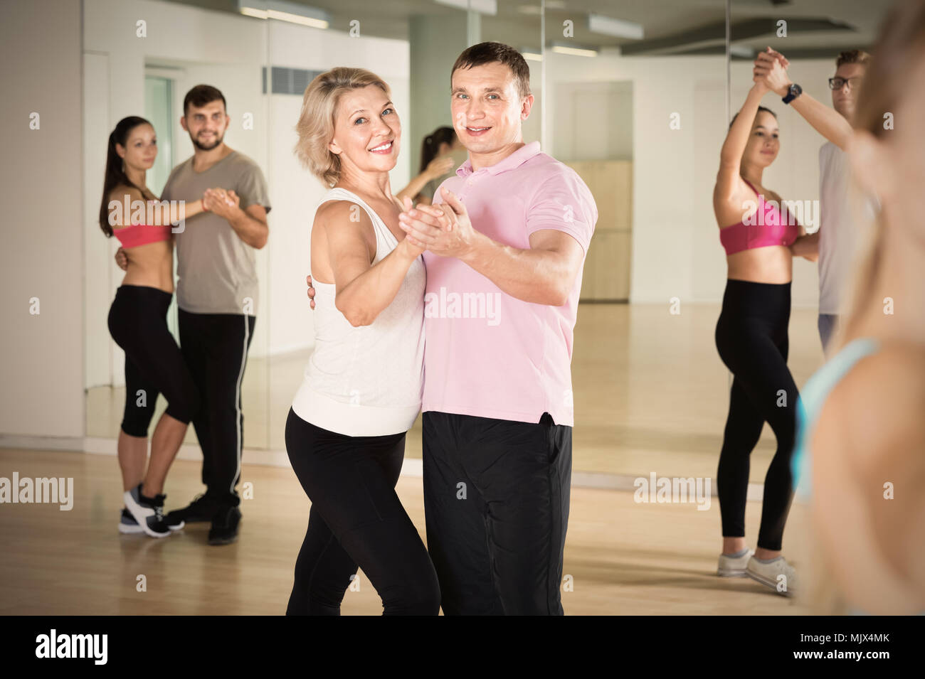 Happy positive smiling people of different ages having dancing class in ...