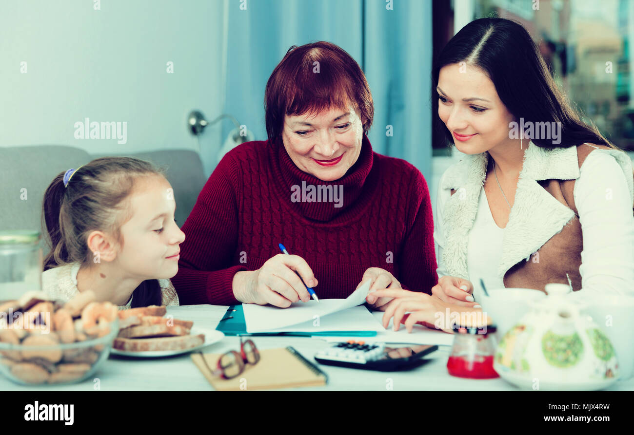 Three generations of happy family working together with documents at ...