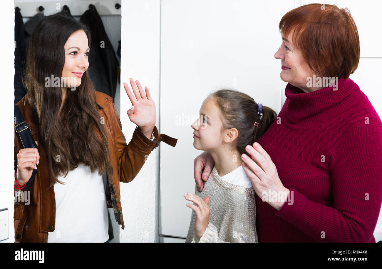 Happy young mother leaving daughter with grandma at home, saying ...