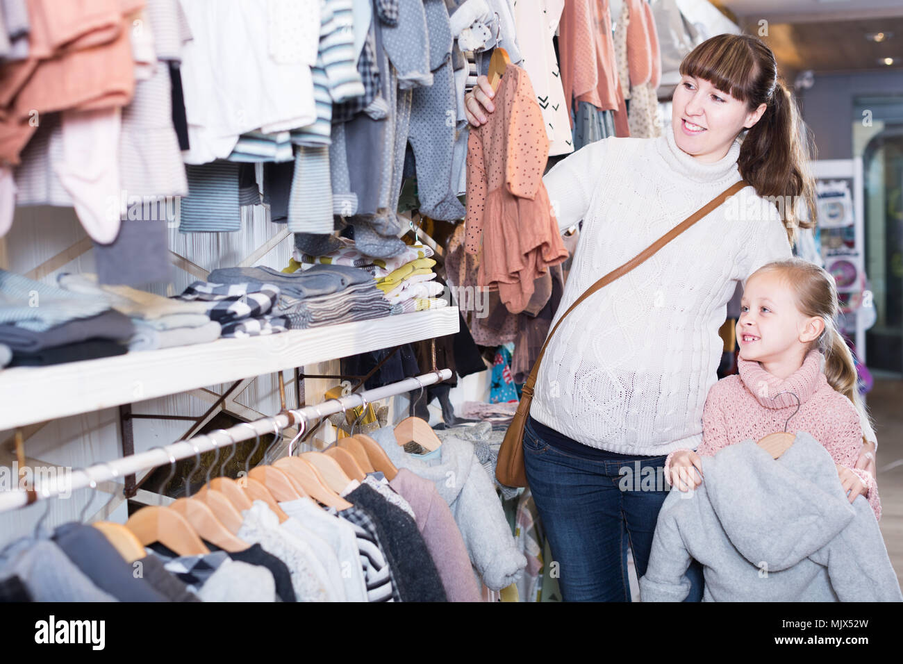 Smiling mother and daughter choosing clothes in a store children's ...