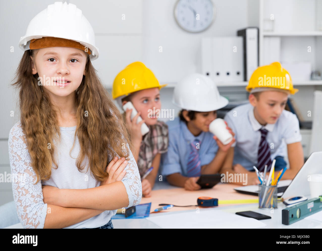 Teenager girl engineer and children near laptop with plan in the office ...