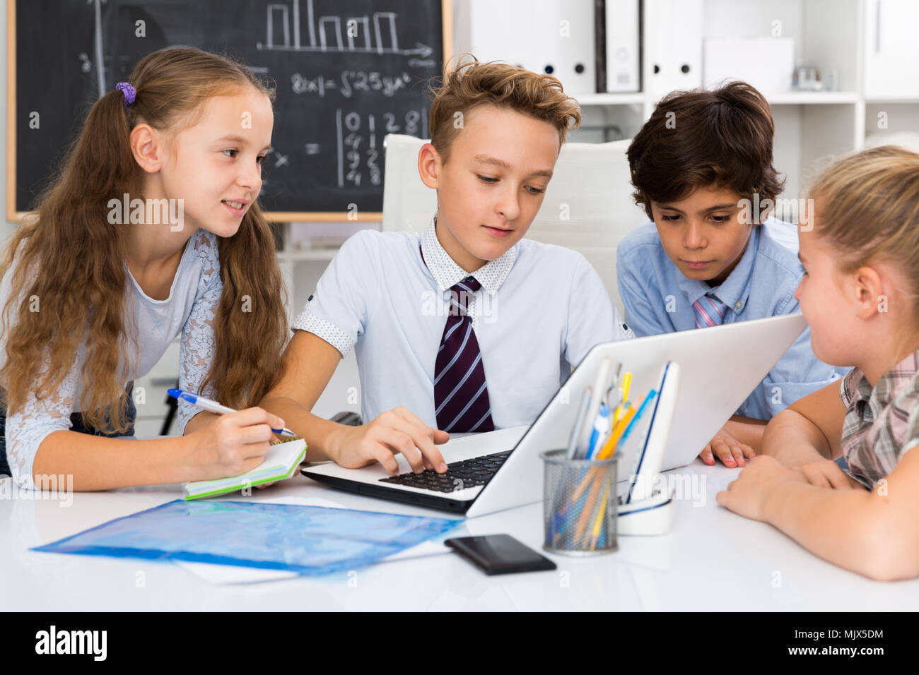 Group of children near laptop talking about mathematics indoors Stock ...