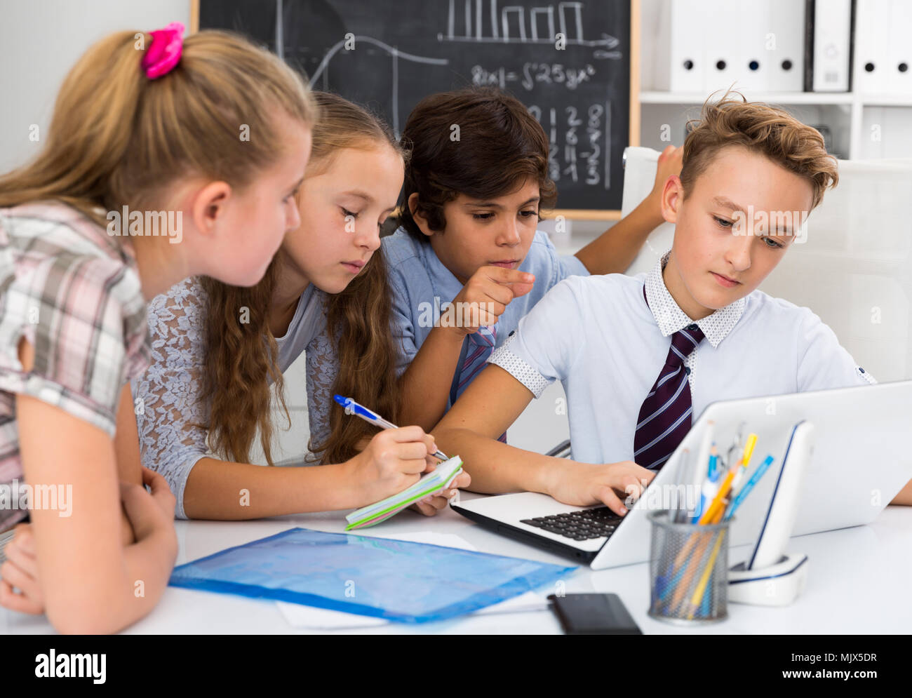 Boys and girls pupils talking near the notebook in the math class Stock ...