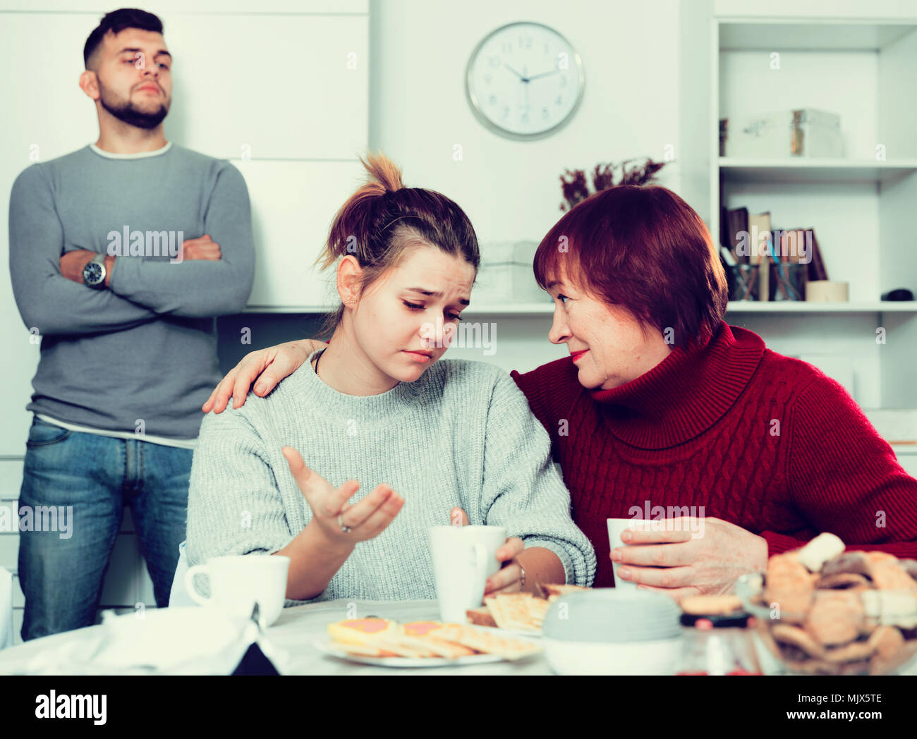 Senior woman calming chagrined girl during her quarrel with boyfriend ...