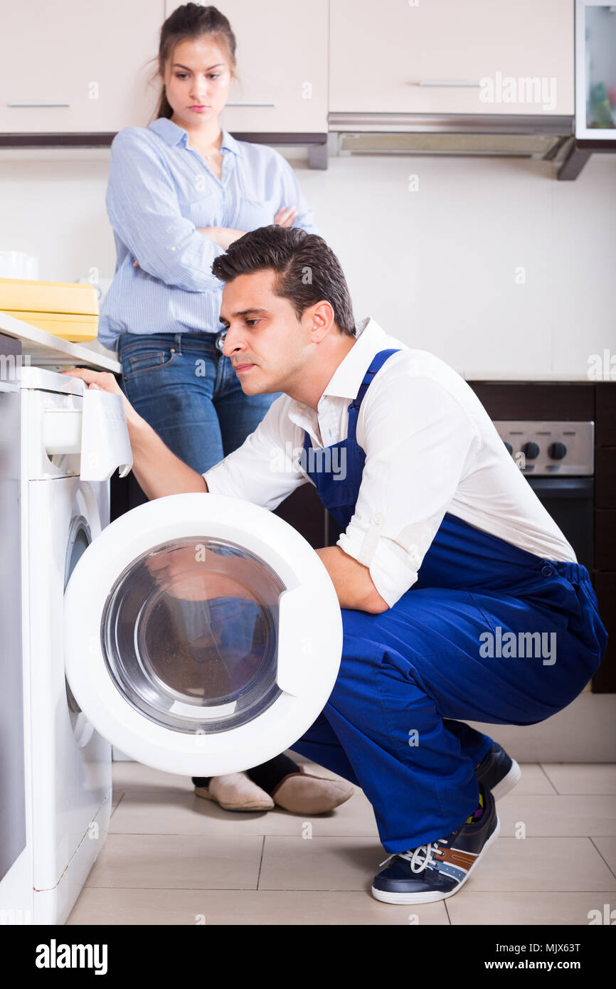 Specialist with tools and young woman washing machine Stock Photo - Alamy