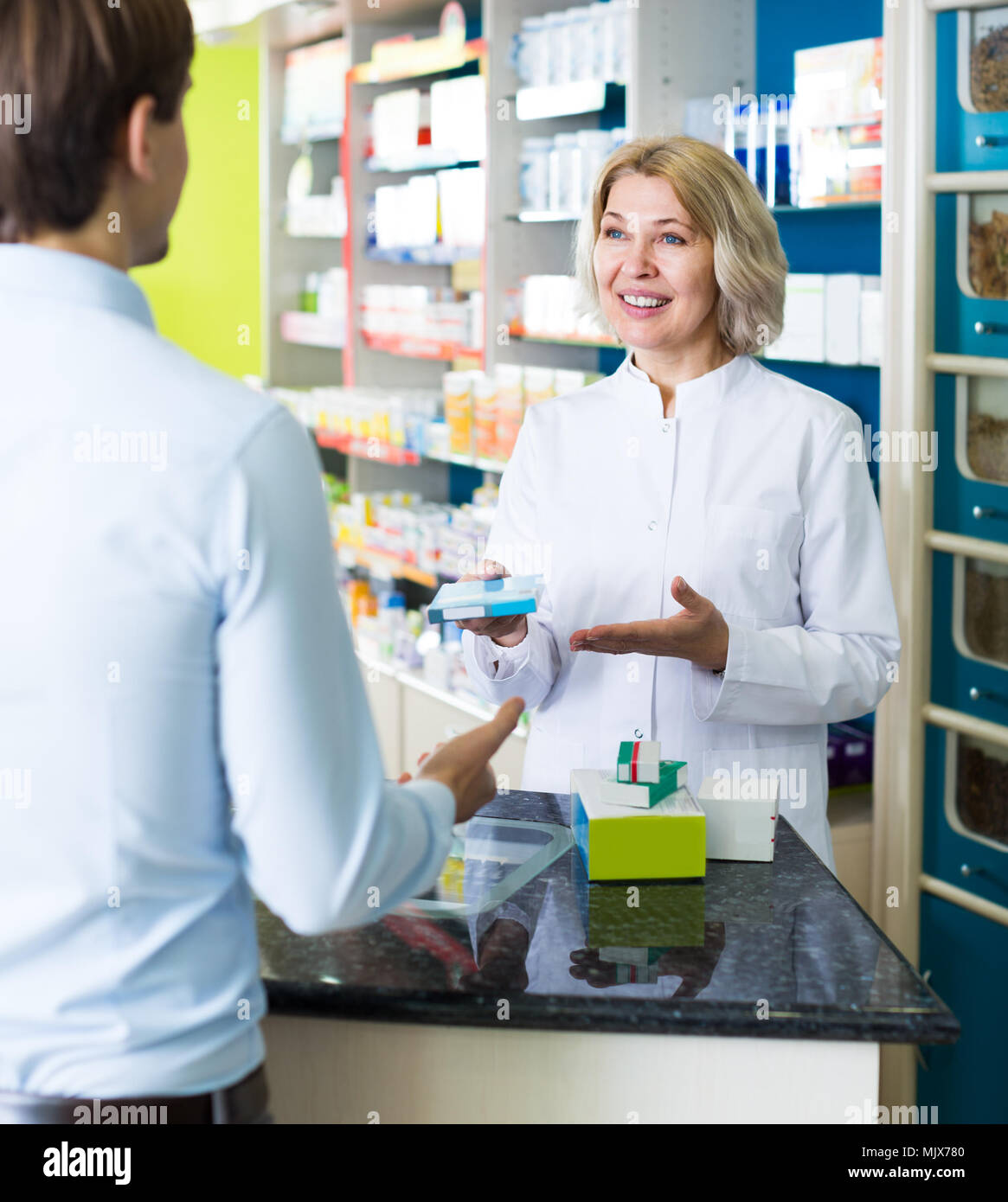 Professional female pharmaceutist helping customer to choose medication ...
