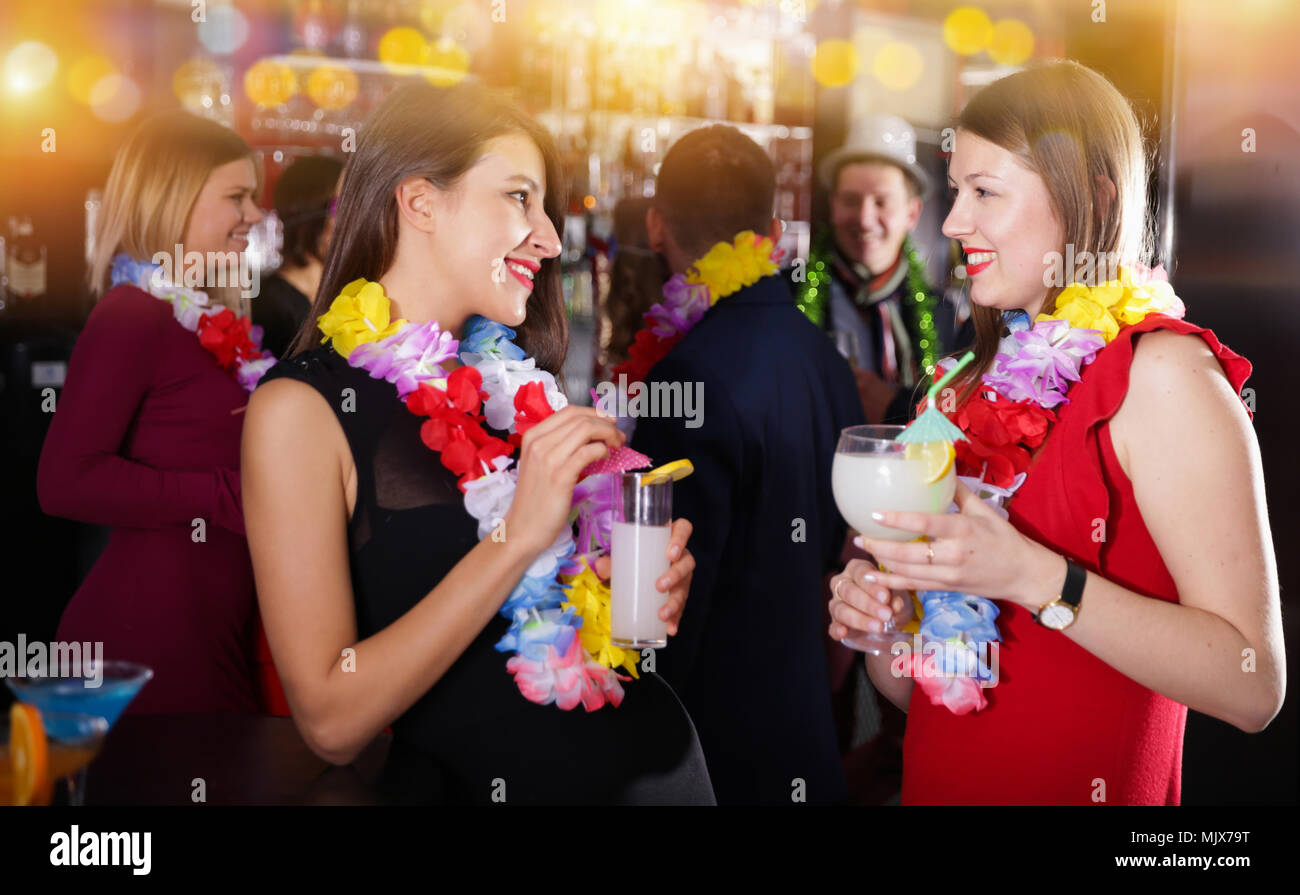 Two young women with cocktails having fun on Hawaiian party at ...