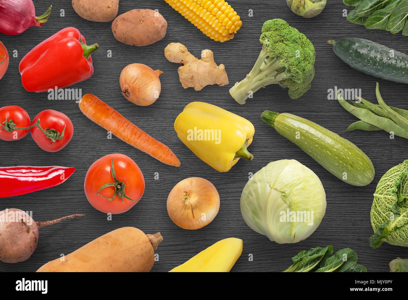 Colorful, red, orange, yellow and green vegetables on black surface ...