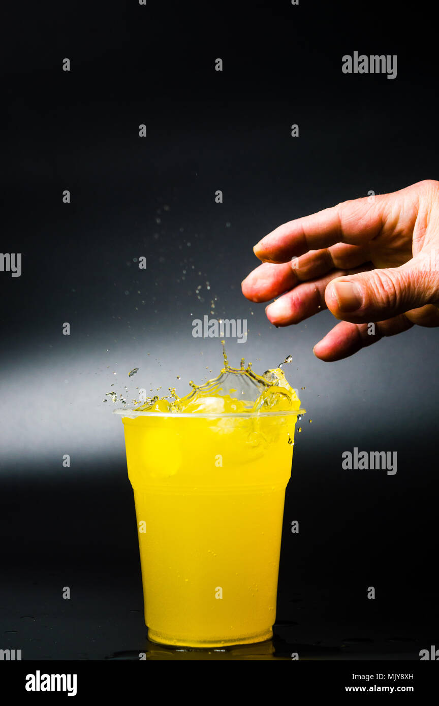 Man adding ice into orange juice against dark background Stock Photo ...