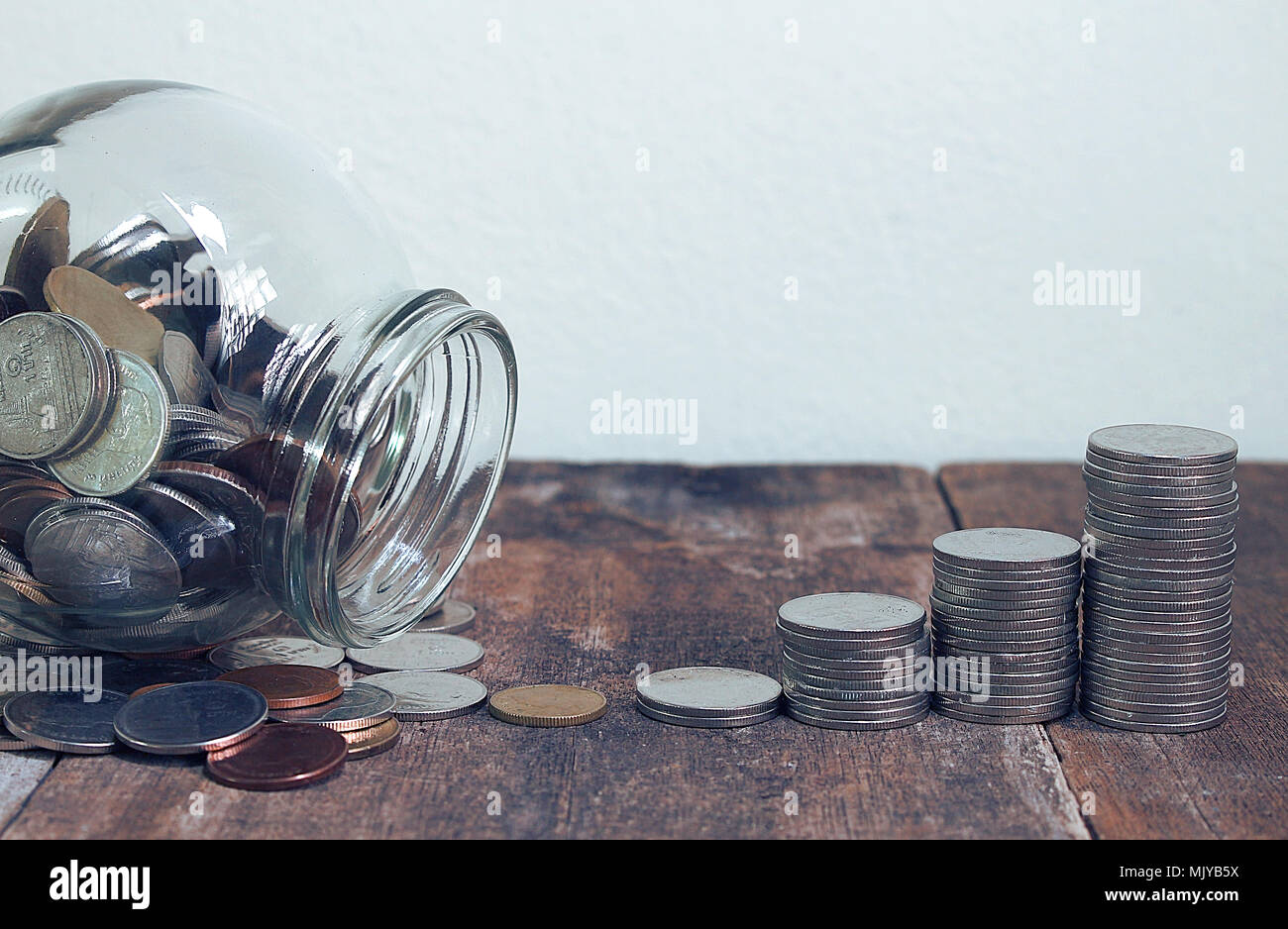 Money spill out from cup glass and stack of coin Stock Photo - Alamy