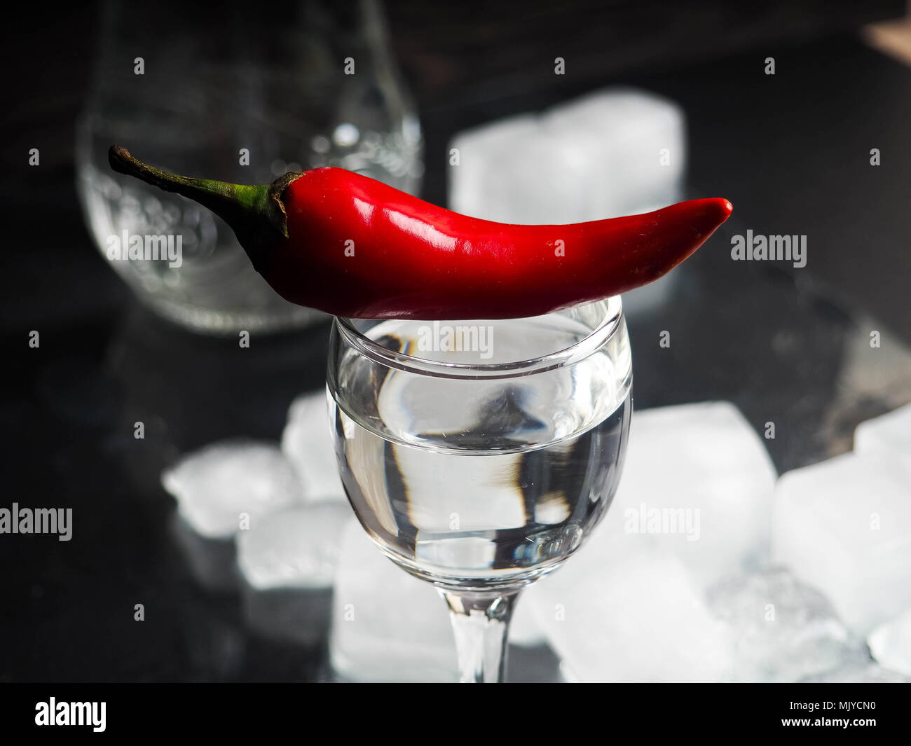a shot of vodka, an alcoholic beverage, next to ice, fire, ice, red ...