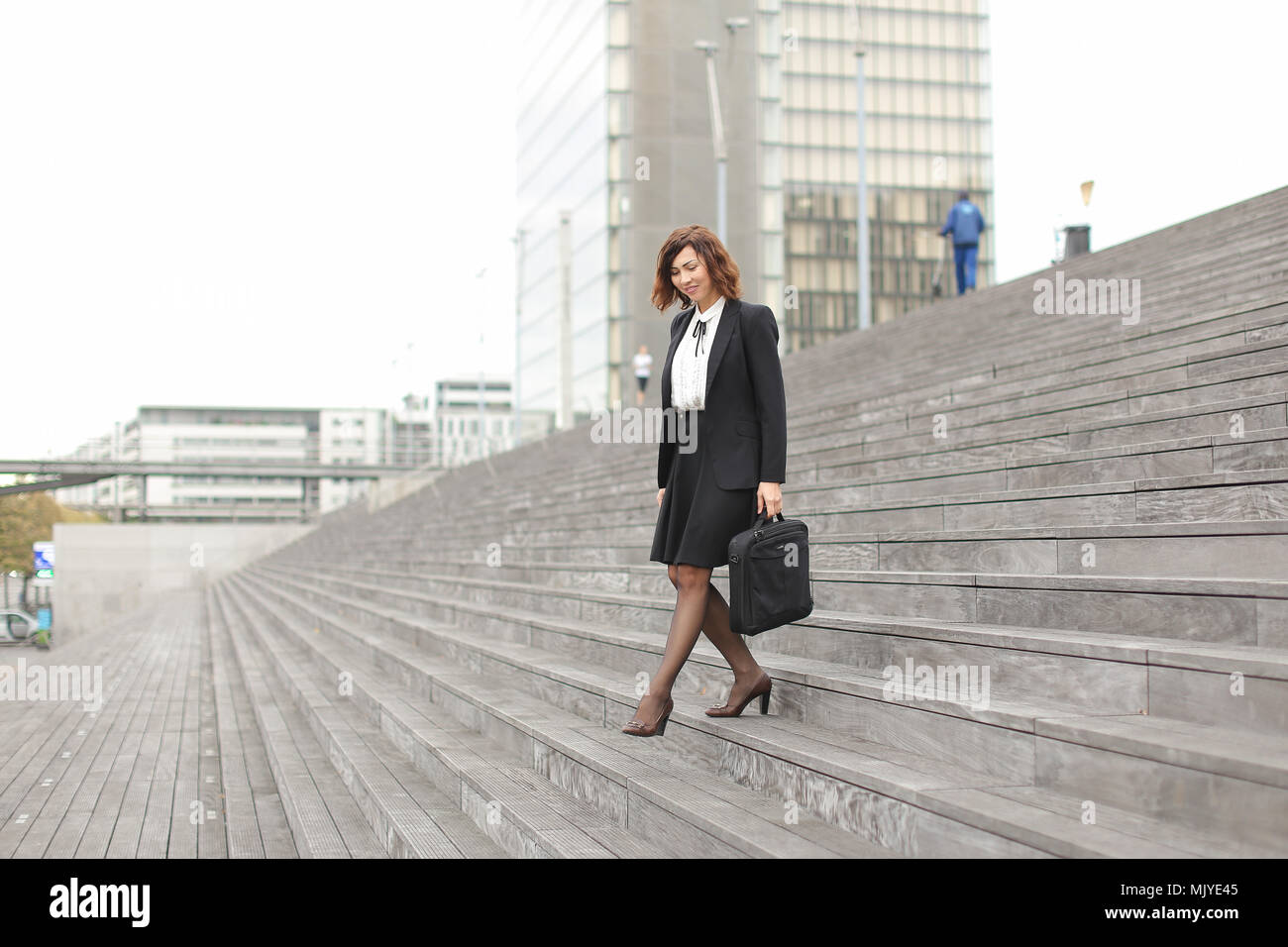 American female manager going down on stairs in high buildings ...