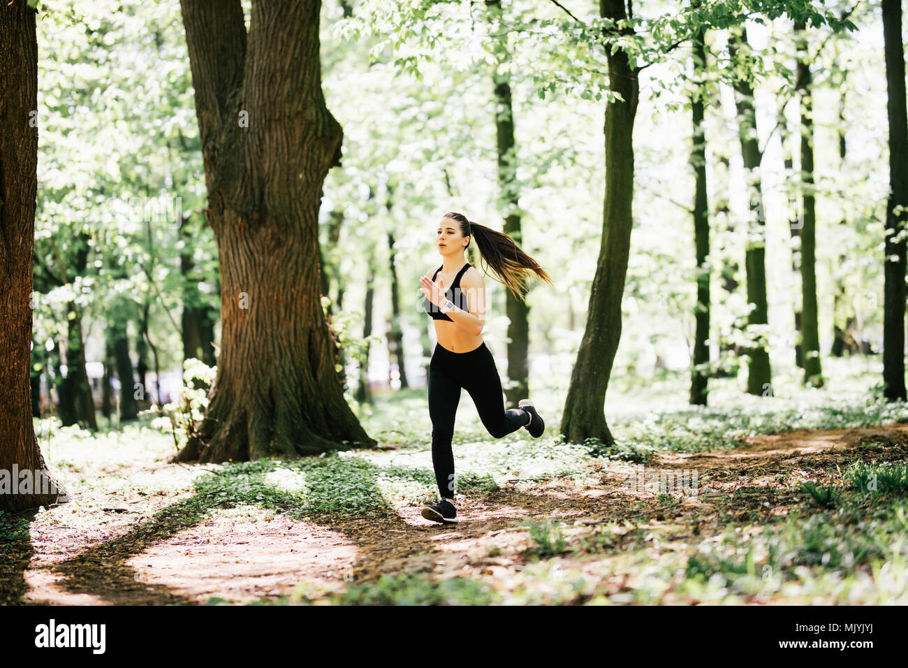 Beautiful young woman in black top jogging in park. Healthy girl ...
