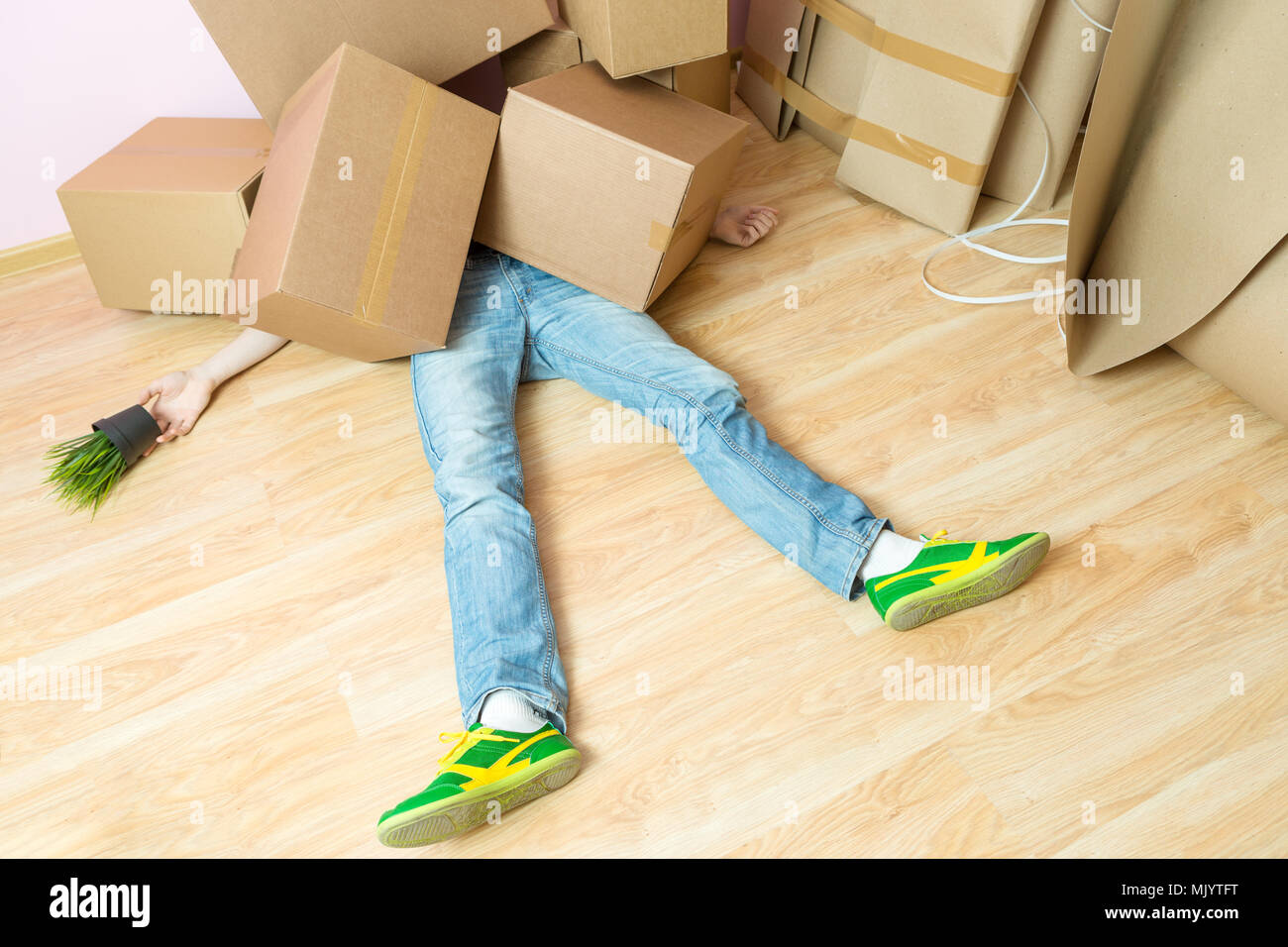 Picture of man in jeans lying under cardboard boxes Stock Photo - Alamy