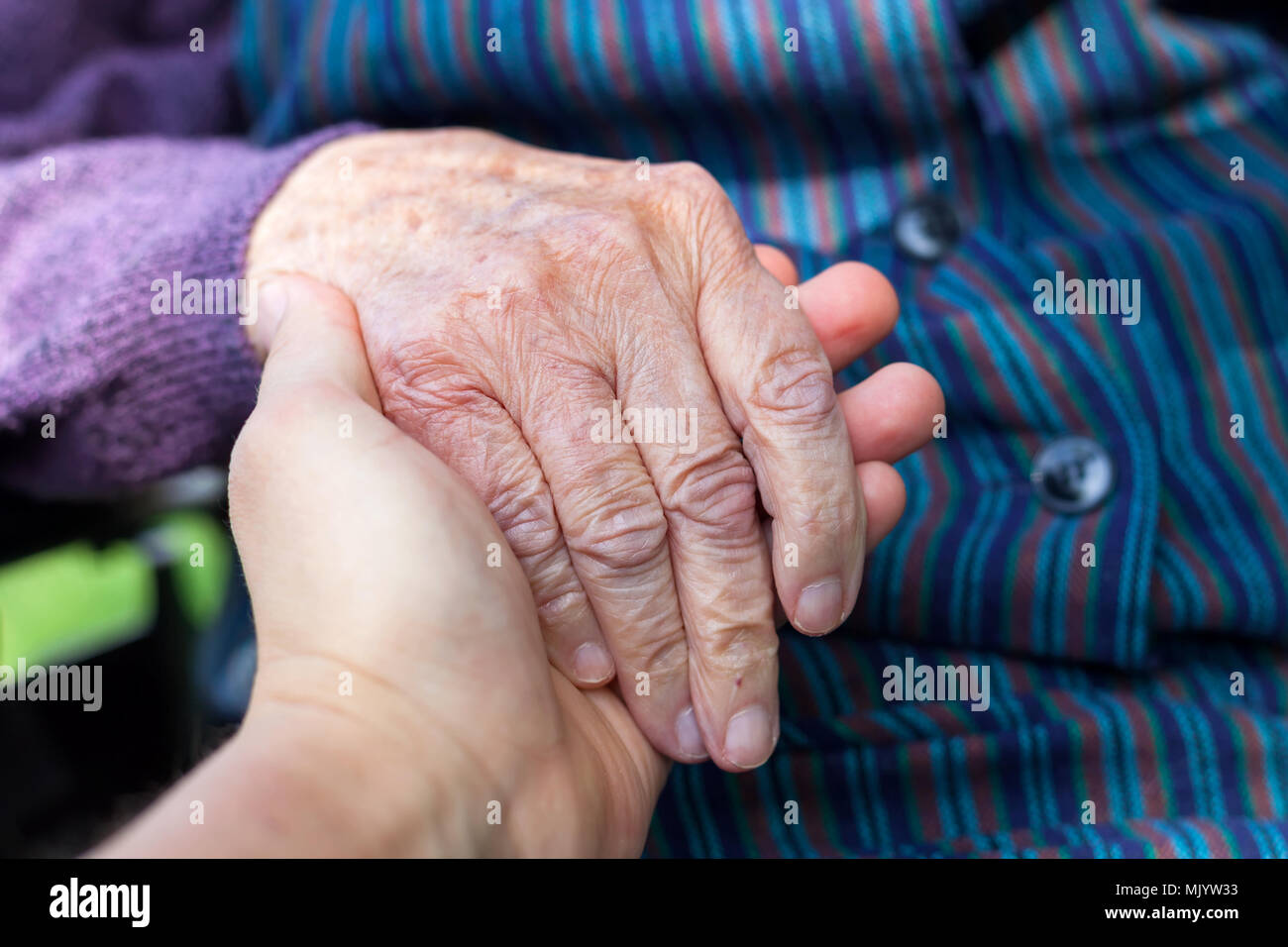 Close up picture of elderly disabled female hands with loving caregiver ...
