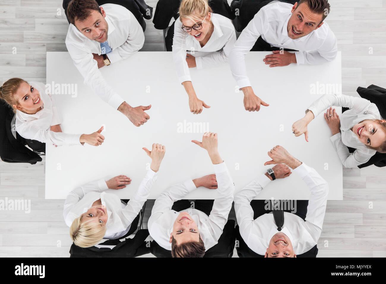 Business people showing thumbs up sitting around white conference table ...