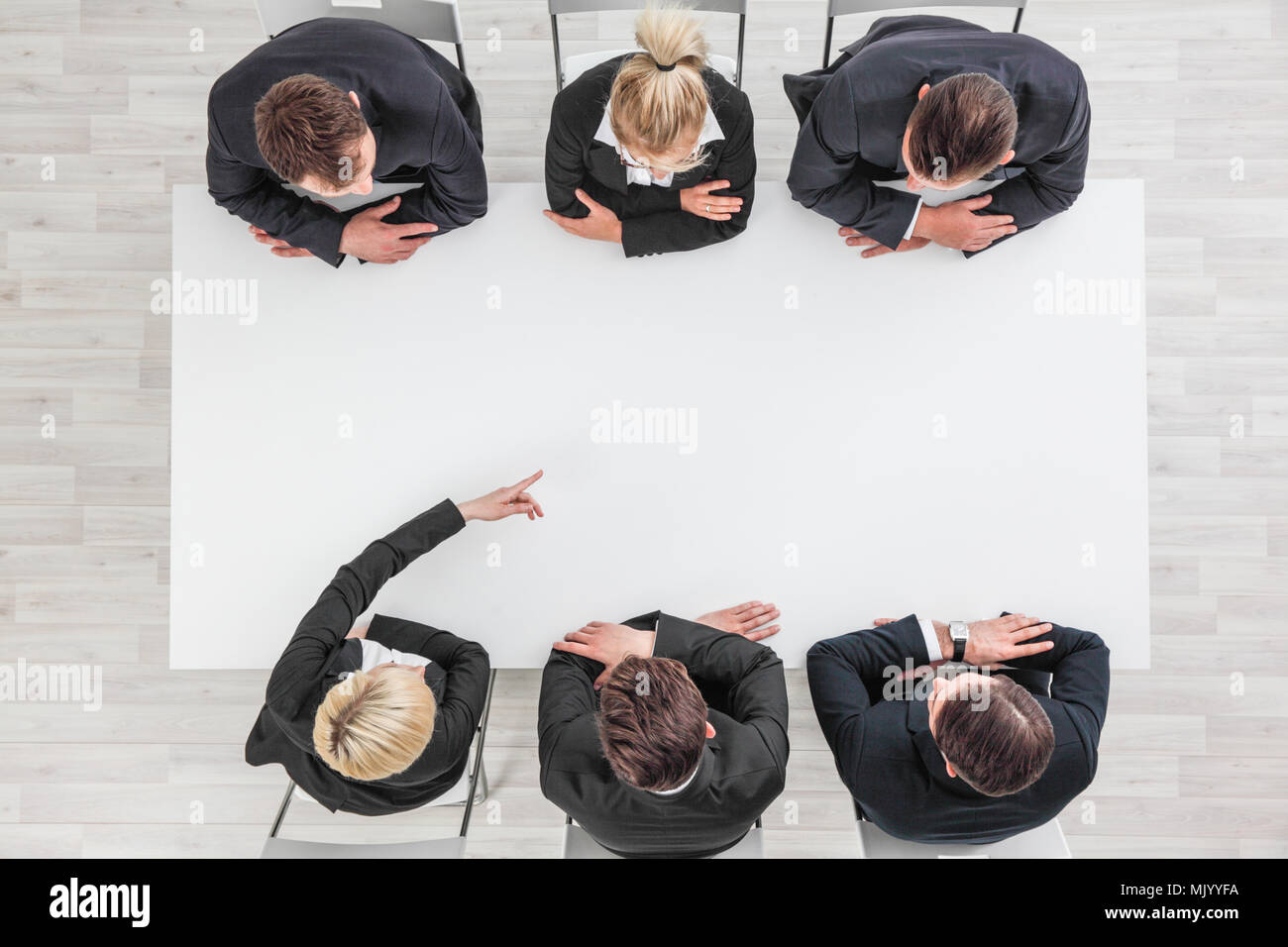 Business people sitting around empty table, business woman pointing to ...