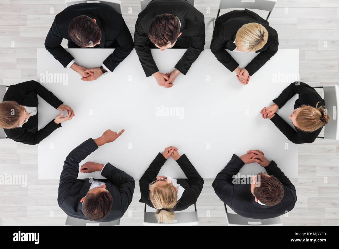 Business people sitting around empty table, business woman pointing to ...