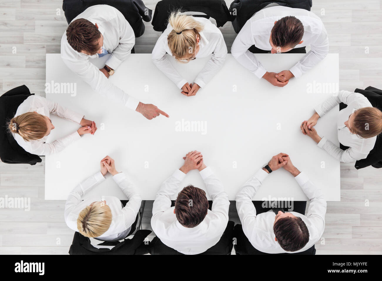 Business people sitting around empty table, business woman pointing to ...
