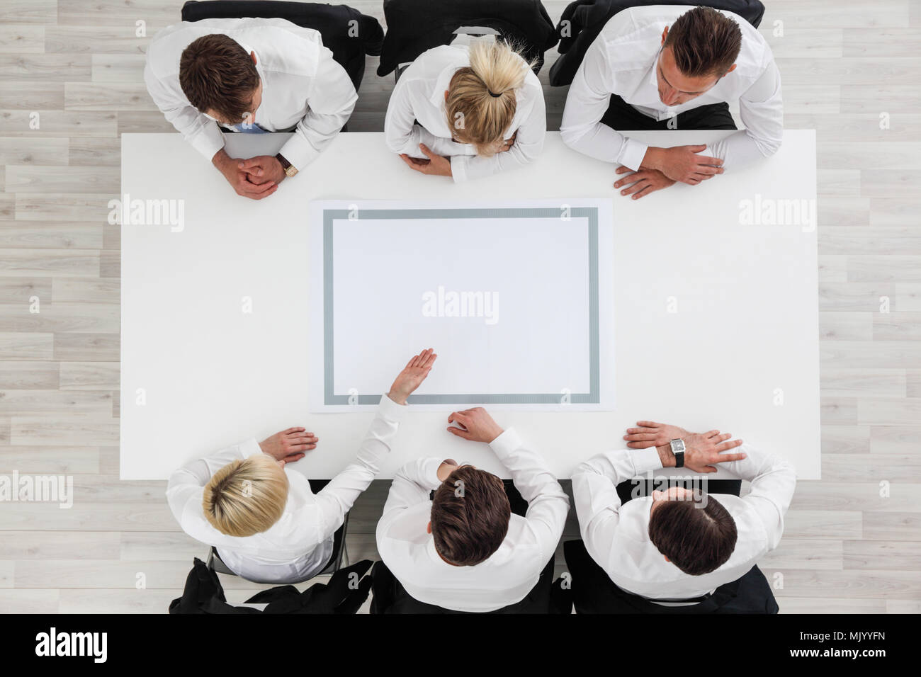 Business people sitting around empty table, business man pointing to ...