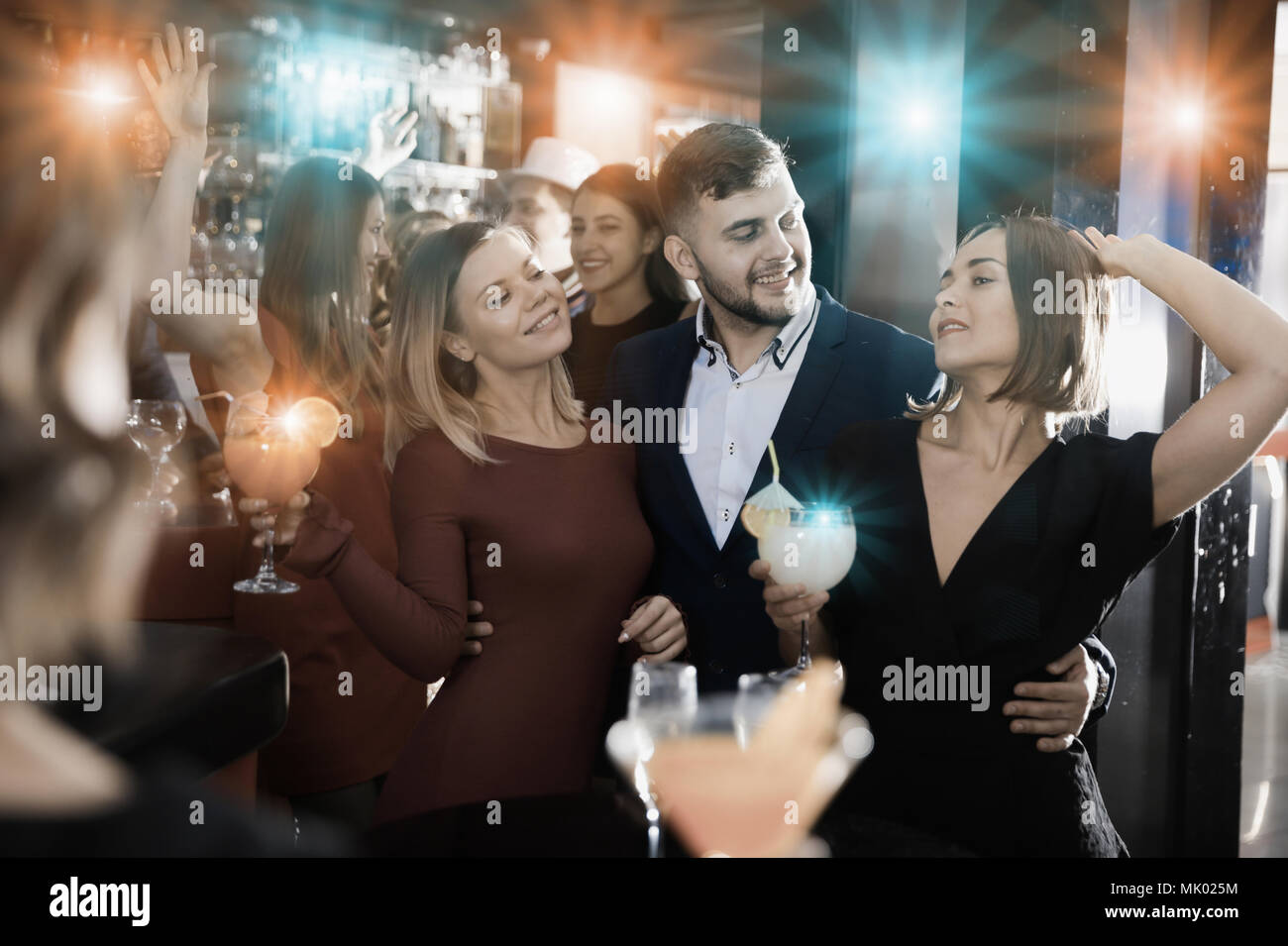 Young man and two women with cocktails having fun at nightclub Stock ...